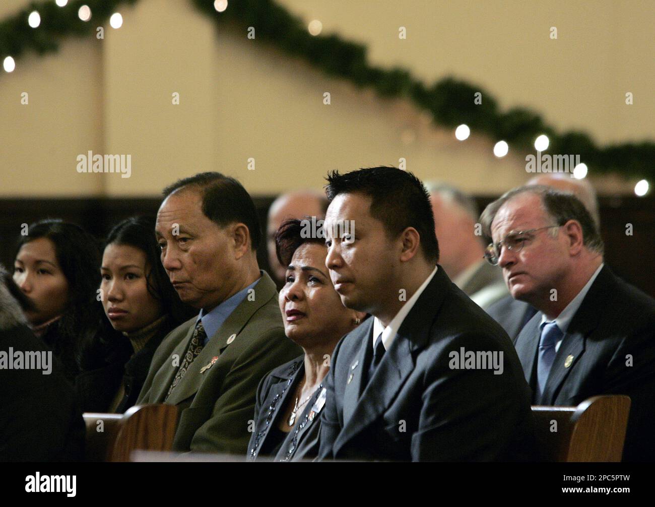 Mason Nguyen, foreground right, brother of Jersey City Police officer Robert Nguyen, sits with ...