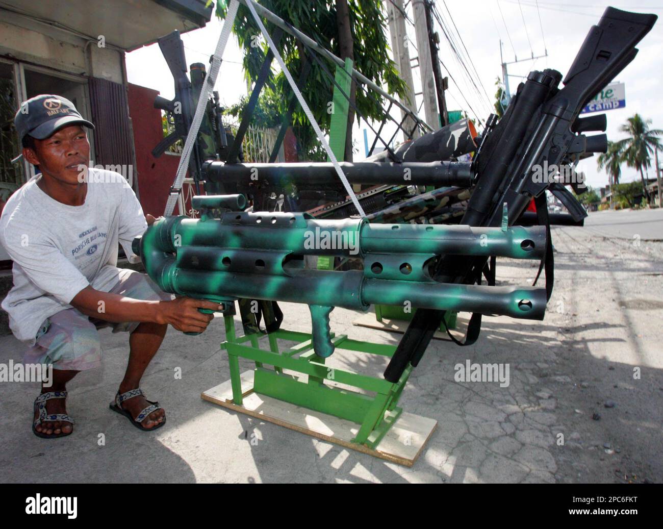 Rolando Santos, test-fires a double barreled toy gun they sell on the ...