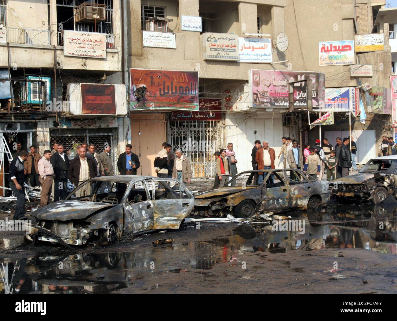 Iraqis look at cars destroyed in a car bomb explosion in the New ...