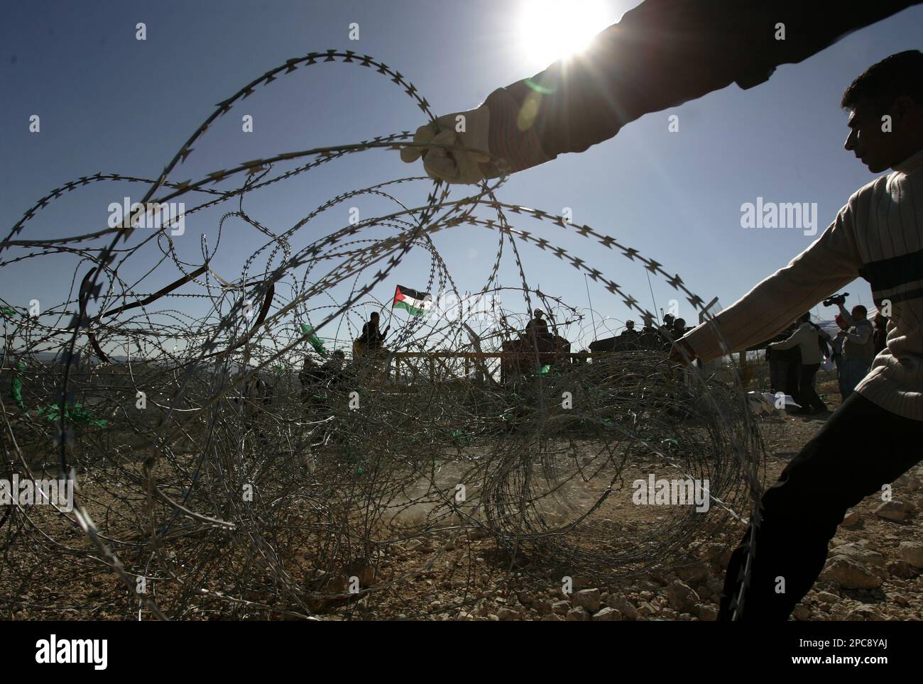 Palestinian demonstrators try to remove razor wire from a fence during ...