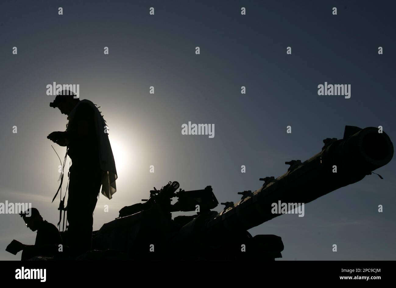 Israeli soldiers pray on top a tank at a military staging area near ...