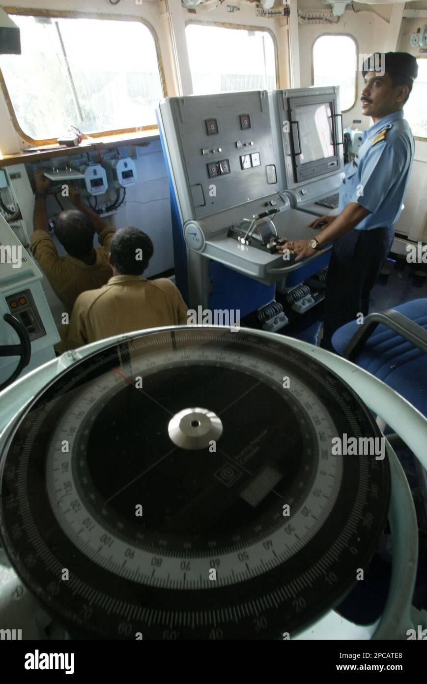 An Indian Navy officer, right, checks an instrument as mechanics, below ...