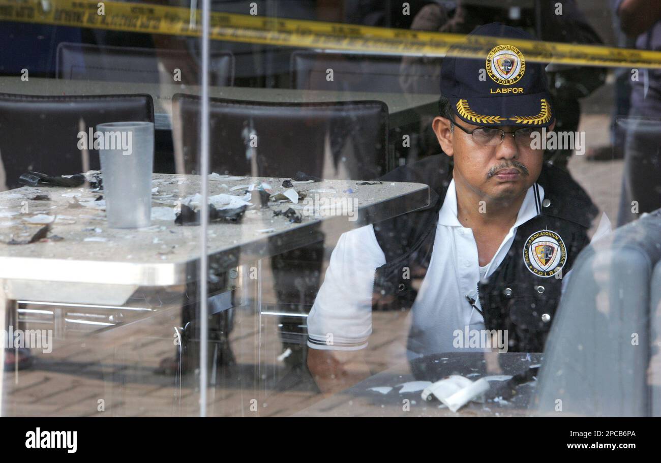 A member of Indonesian Police forensic unit inspects damages at an A&W ...