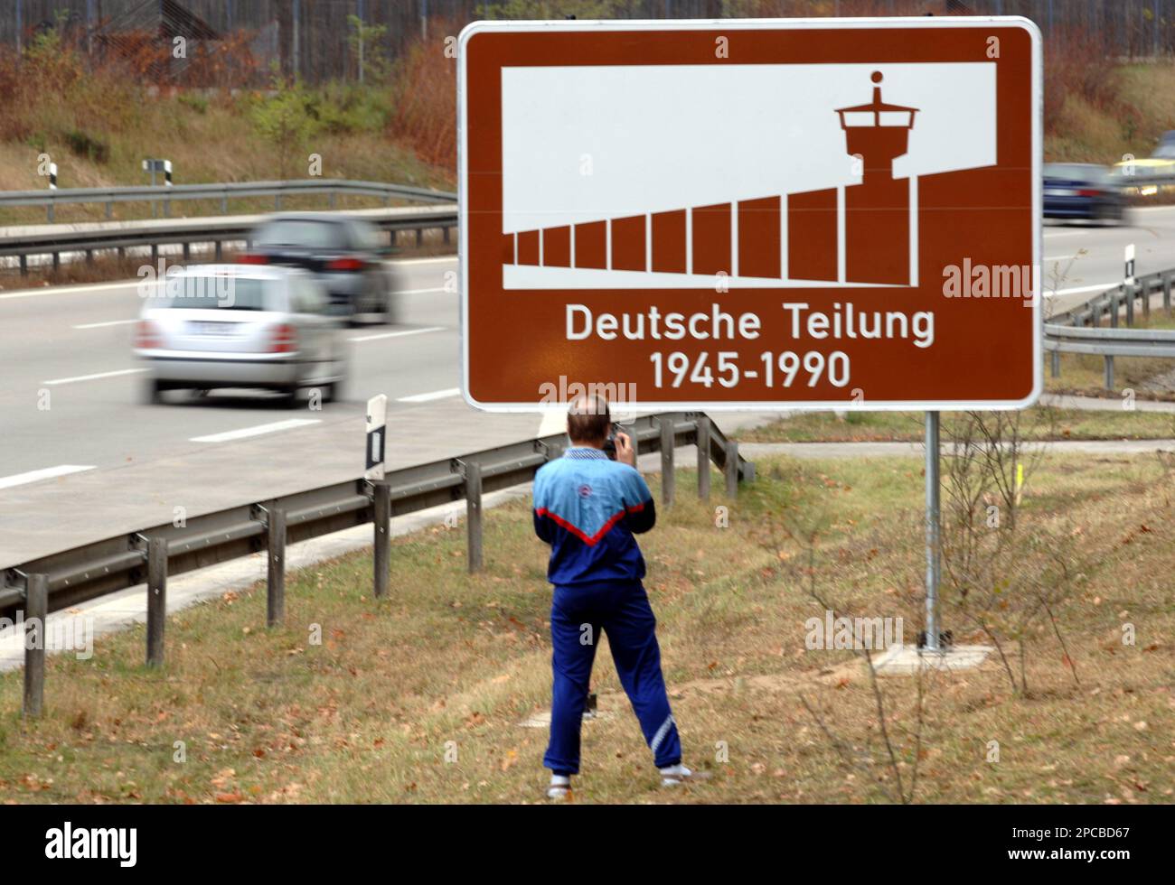 An unidentified man takes a picture of a sign reading "German divide ...