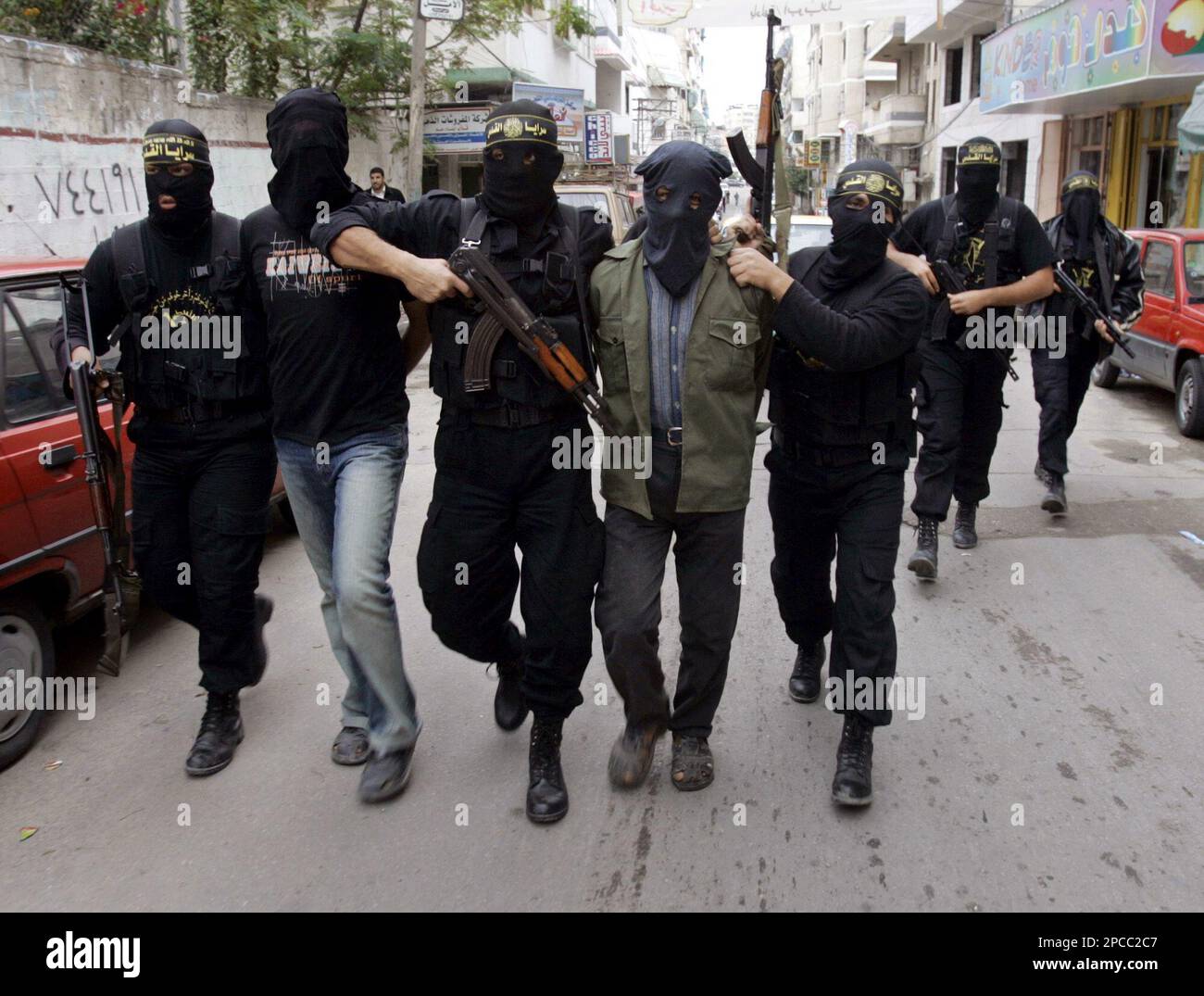 Palestinian Islamic Jihad masked gunmen hold up their guns as they hold ...