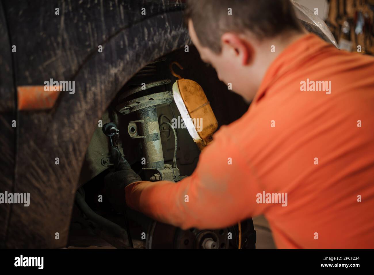Mechaniker repariert den Unterwagen des Fahrzeugs. Ein Mann repariert ...