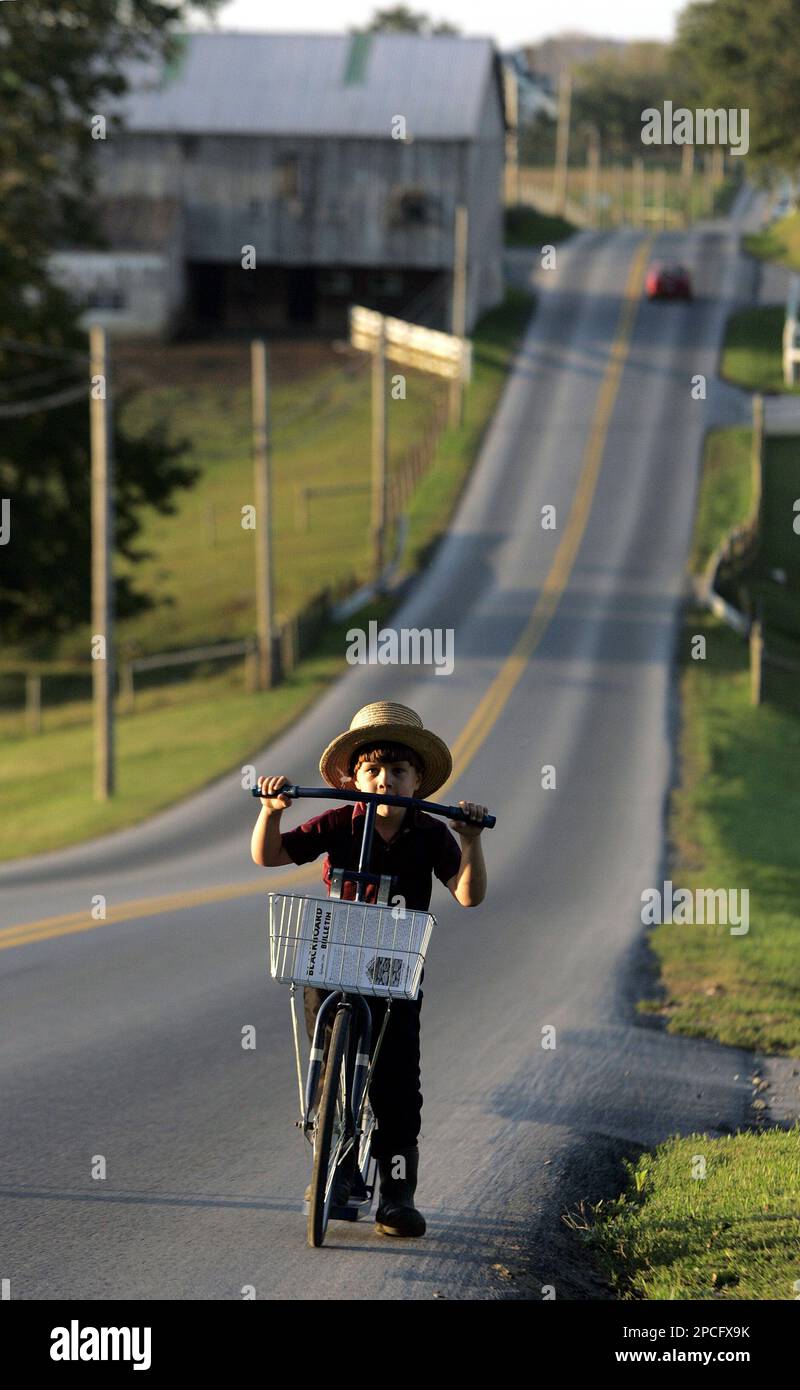 An Amish youngster rides his scooter along a country road near New ...