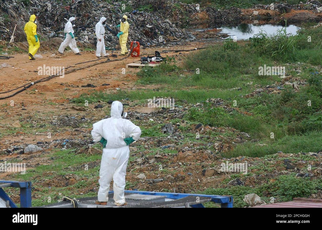 Waste removal experts work to remove hazardous black sludge from a ...