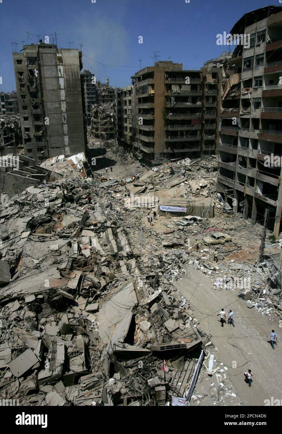 Lebanese residents walk through the rubble of apartment blocks ...