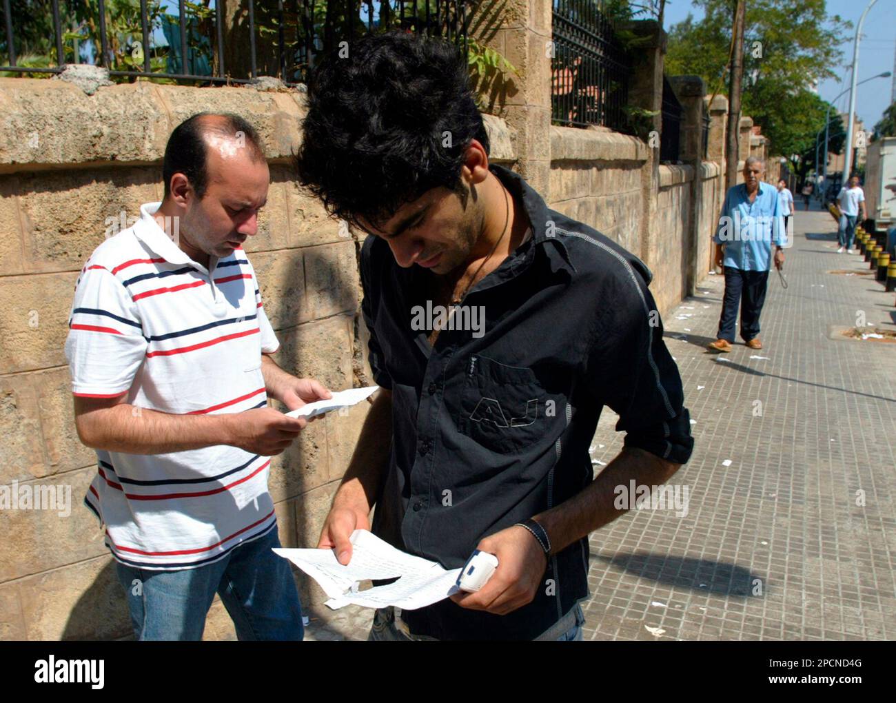 Lebanese men read leaflets dropped by Israeli warplanes, in Beirut ...