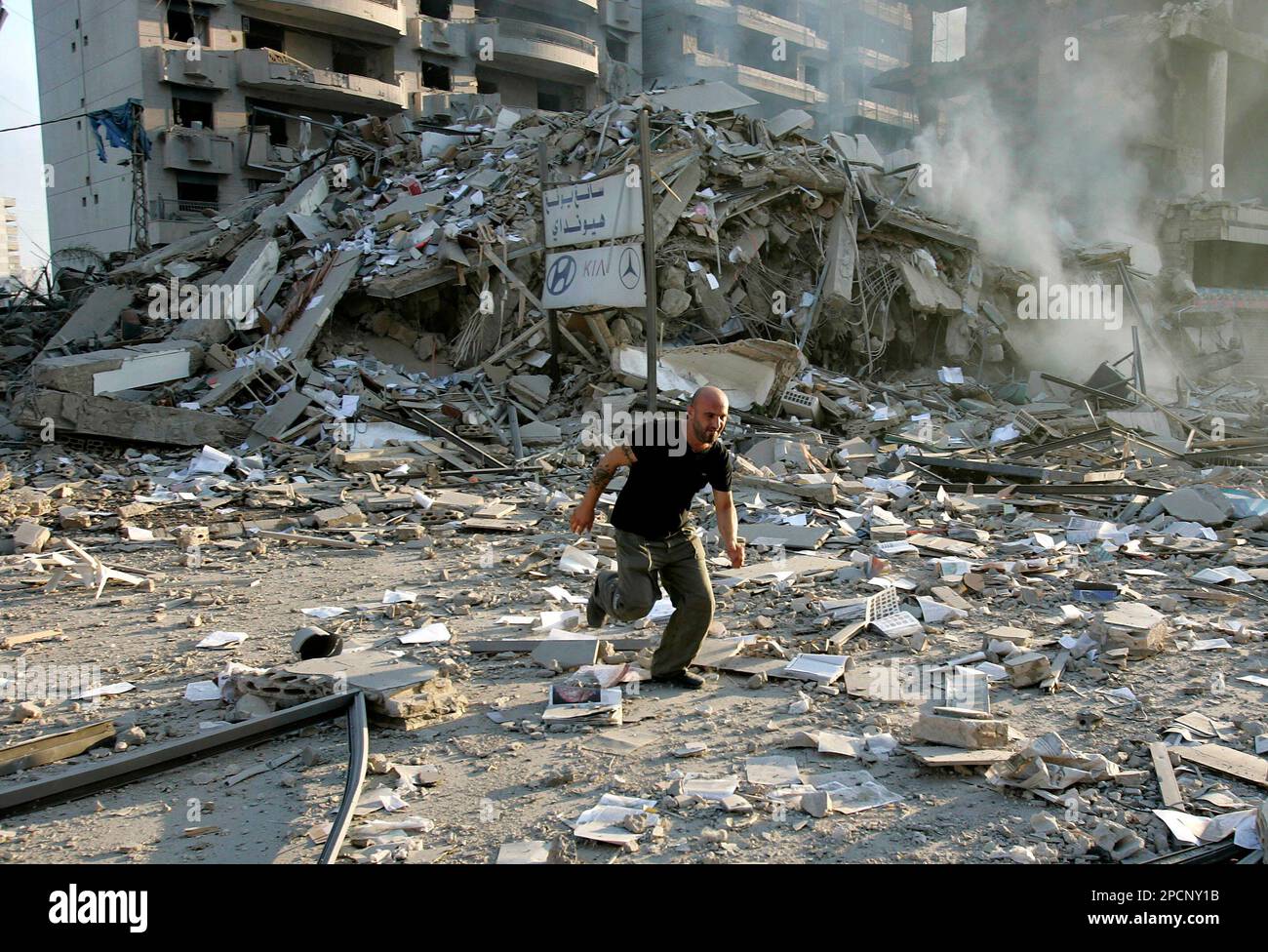 A Lebanese man runs amongst the rubble of a destroyed apartment ...