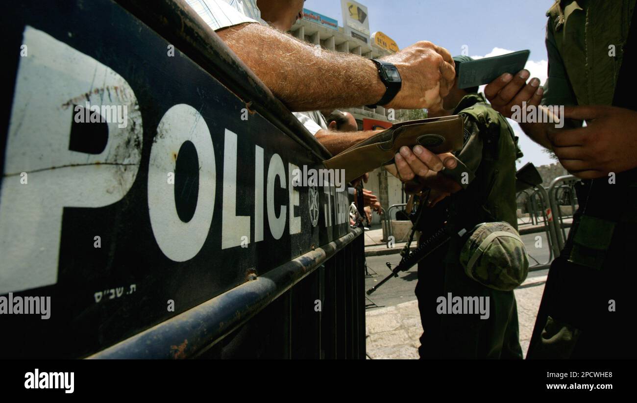 An Israeli border police officer checks identification cards of a ...