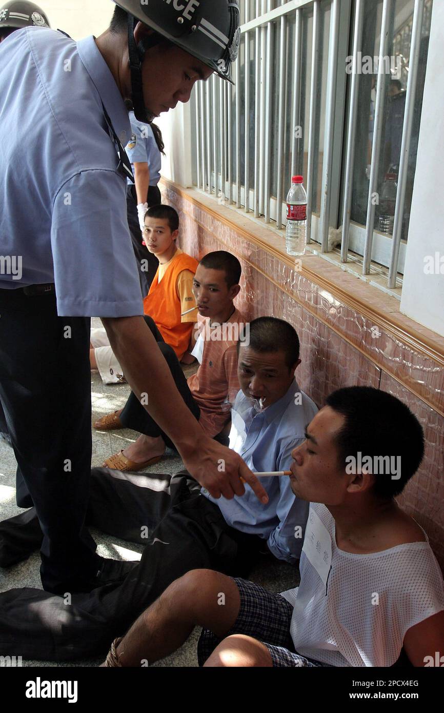 A Chinese police officer lights a cigarette for drug trafficker Wang ...