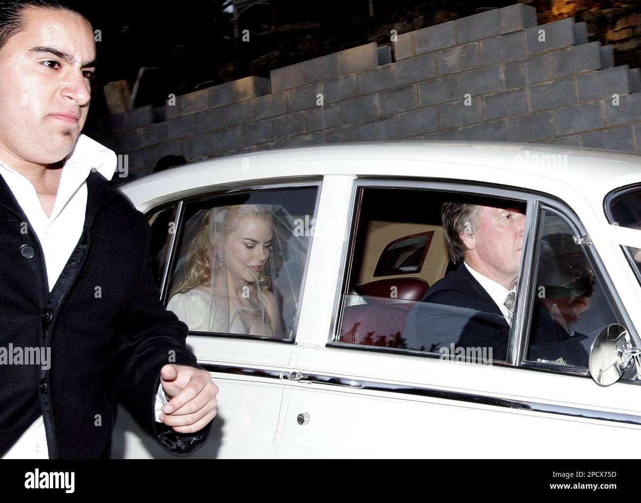 A bodyguard, left, runs next to a car with Oscar winning actress Nicole ...
