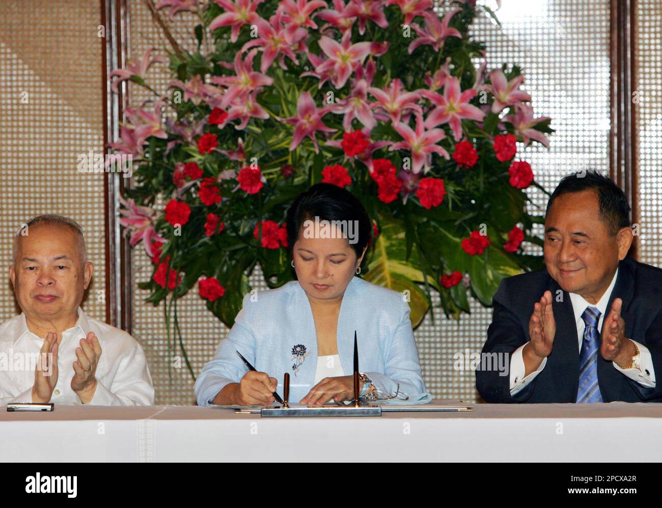 President Gloria Macapagal Arroyo, center, signs into law the bill ...