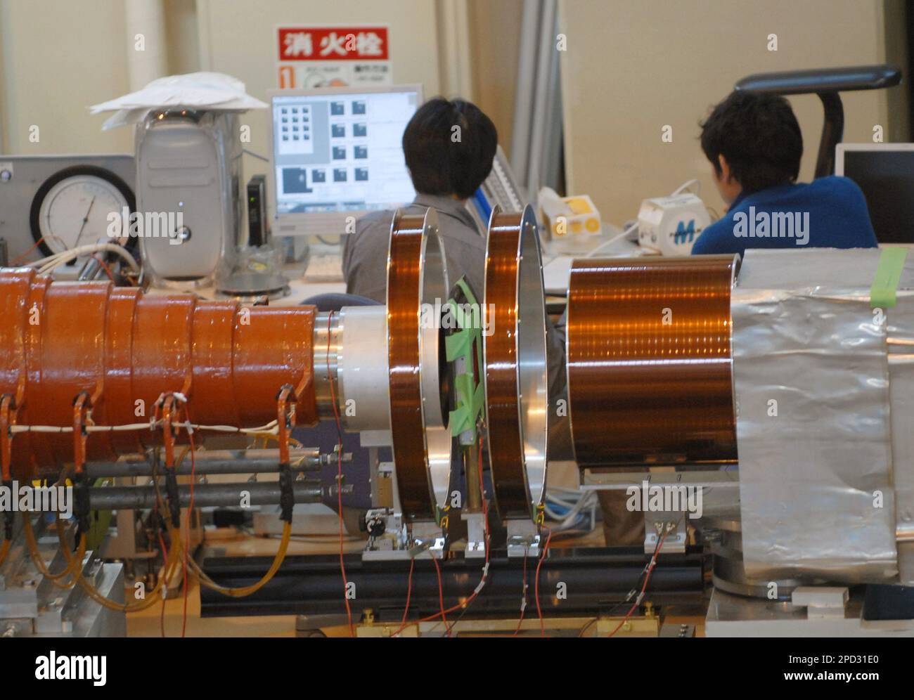Engineers check monitors behind a tube of neutron beam lines connected ...
