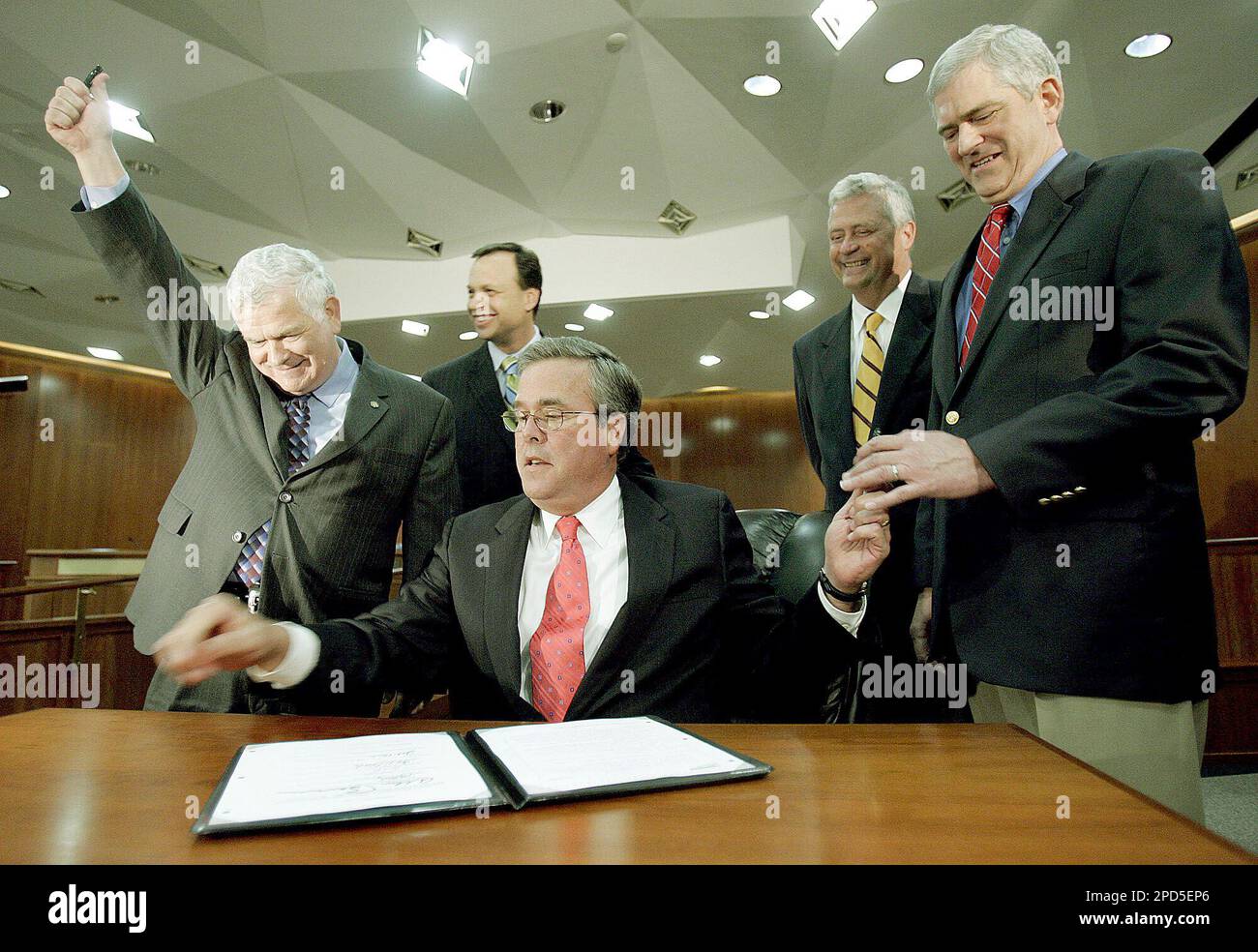 Florida Gov. Jeb Bush, seated, hands outs pens following his signing of ...