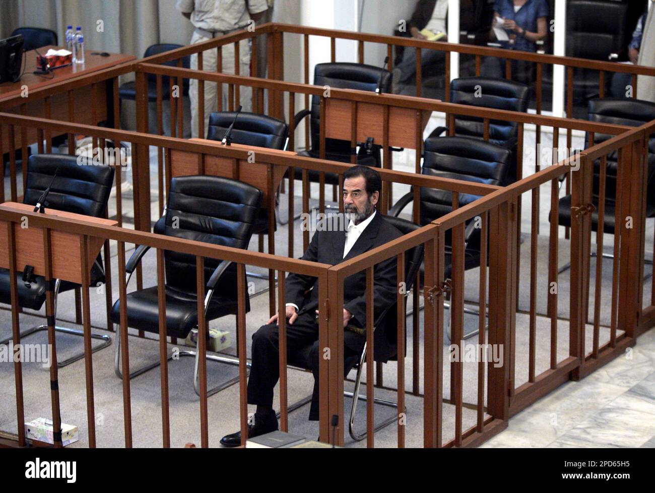 Former Iraqi President Saddam Hussein sits alone in the defendant's ...