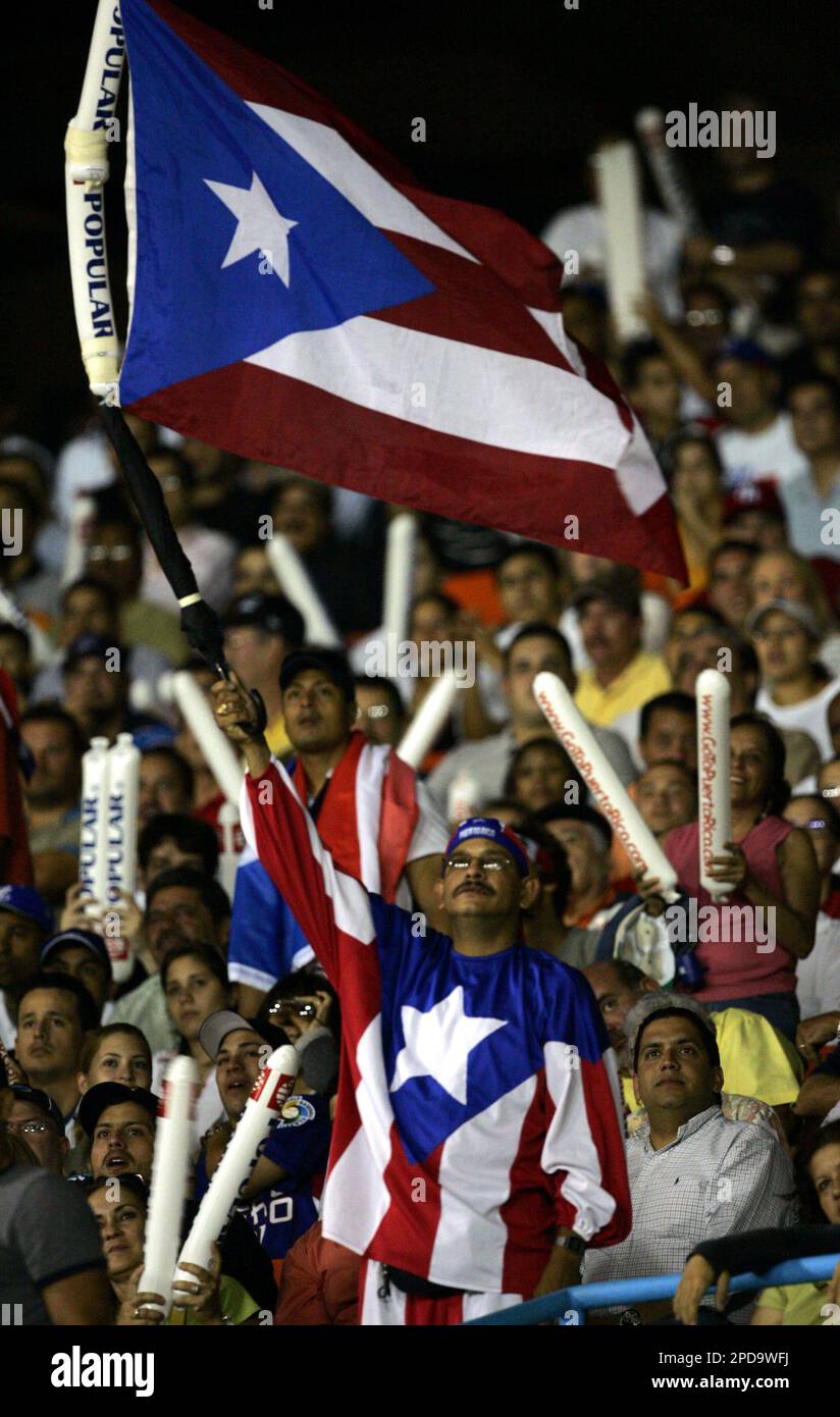 A fan dressed in the design of the Puerto Rican flag waves the flag ...