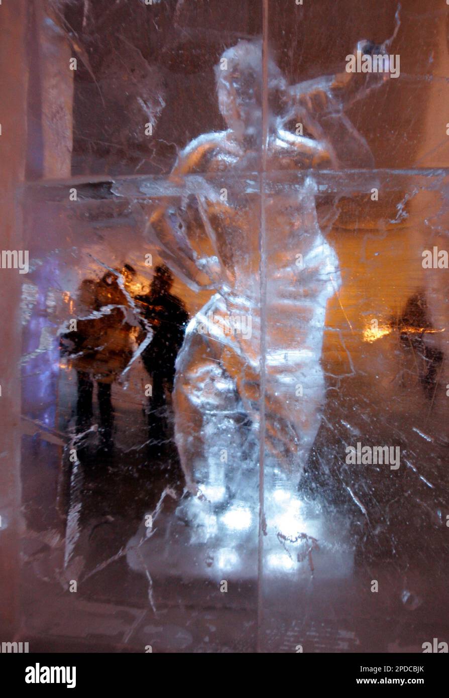 Visitors looking at an ice statue seen through an ice window in the Ice ...