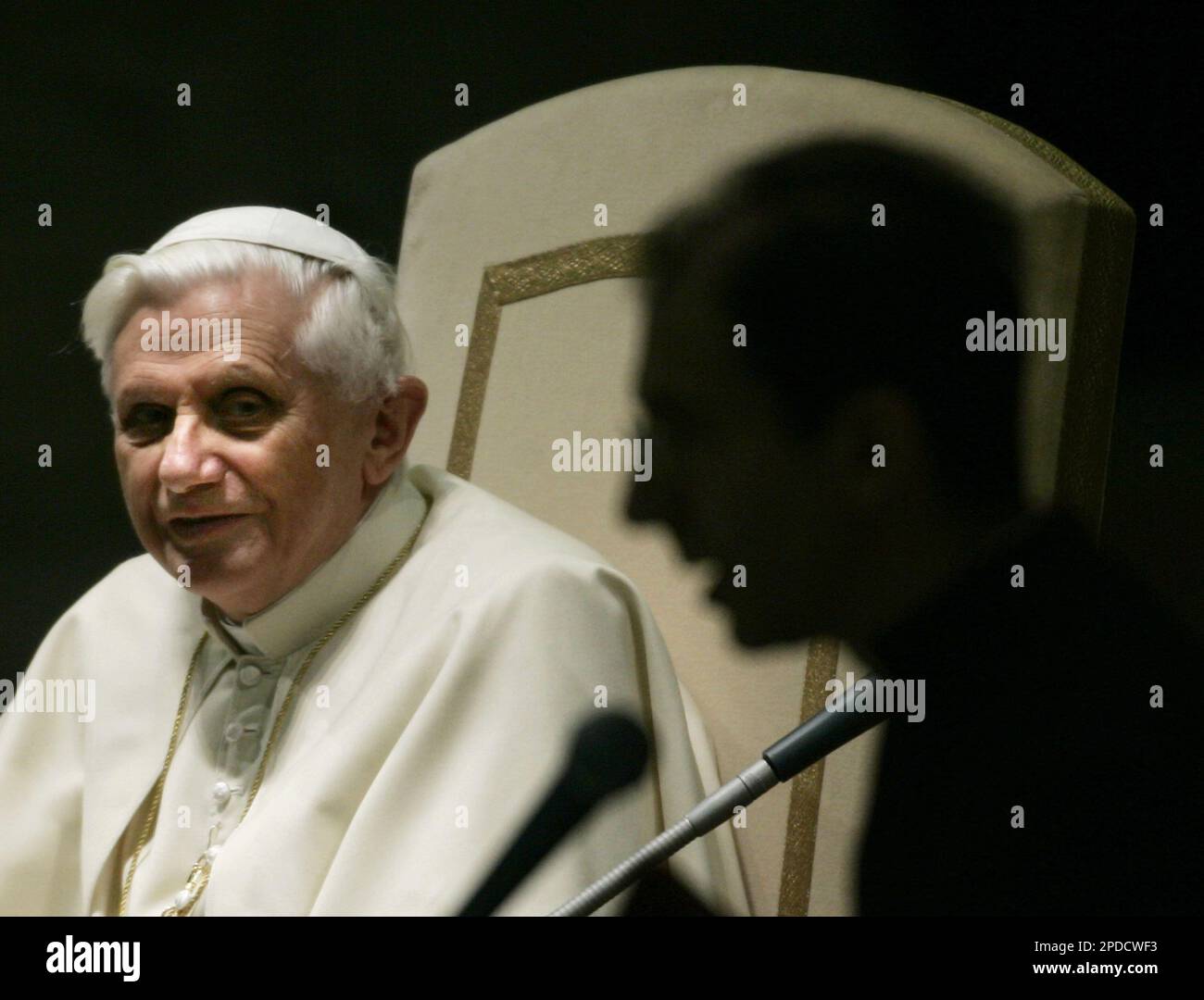 Pope Benedict XVI listens to a priest announcing the group of pilgrims ...