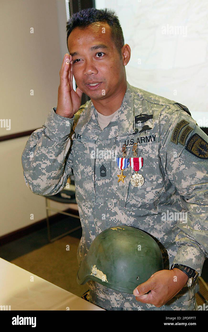 Holding the helmet that still bears a bullet hole, Army Master Sgt ...