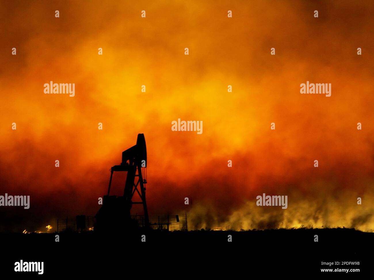 An oil well pump is silhouetted against a grass fire in Guthhrie, Okla ...