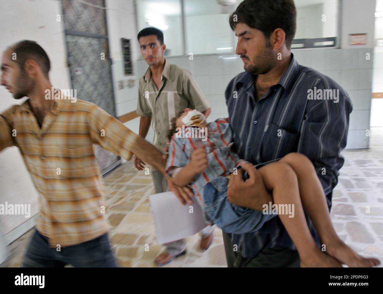 An Iraqi man carries a wounded child into an emergency room in Baghdad ...