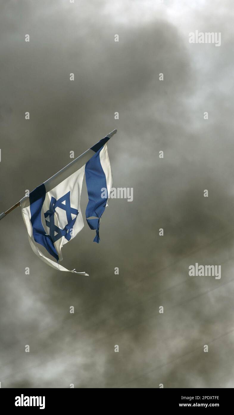 ** RECROP ** A torn Israeli flag flies as smoke billows from the ...