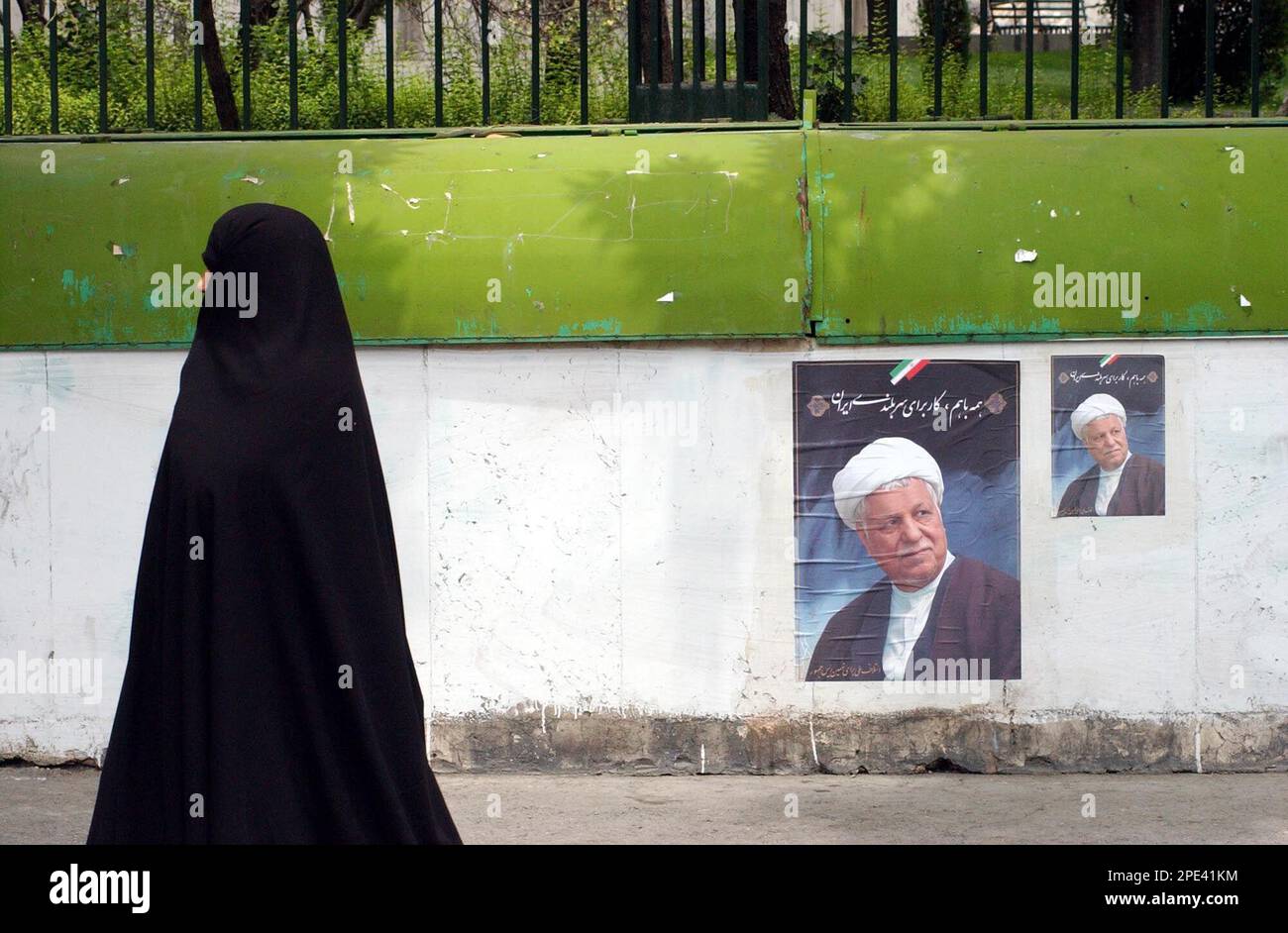 Head-to-toe veiled Iranian woman, walks past the campaign posters of ...