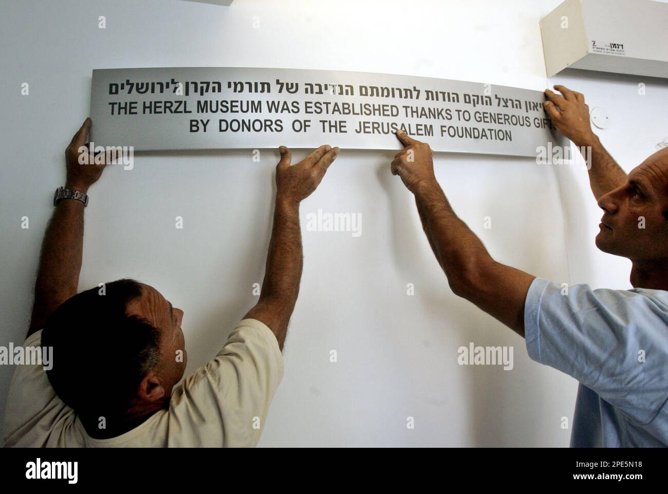Workers fix a plaque at the entrance to the new museum dedicated to ...