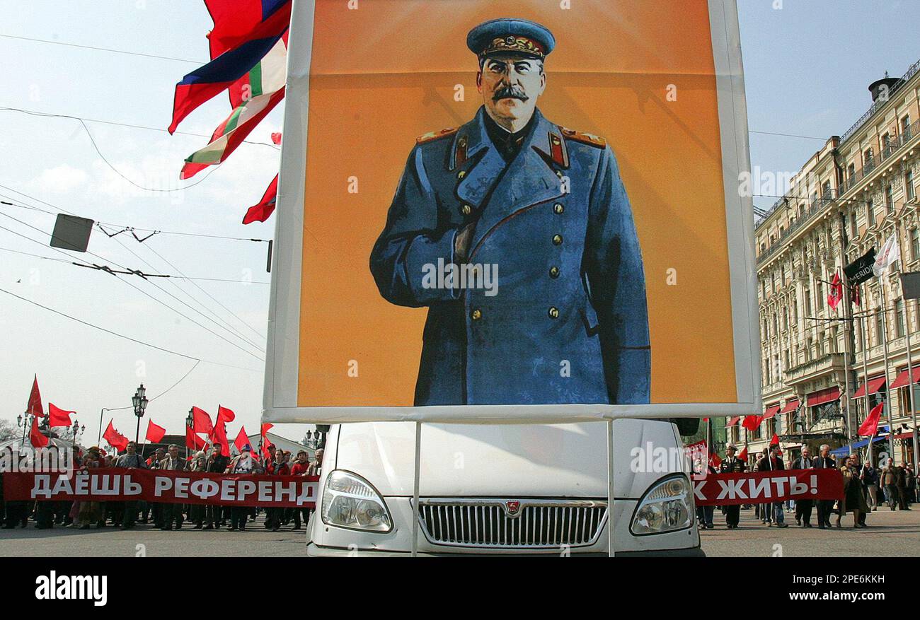 A column of Communists and their supporters follow a portrait of Soviet ...