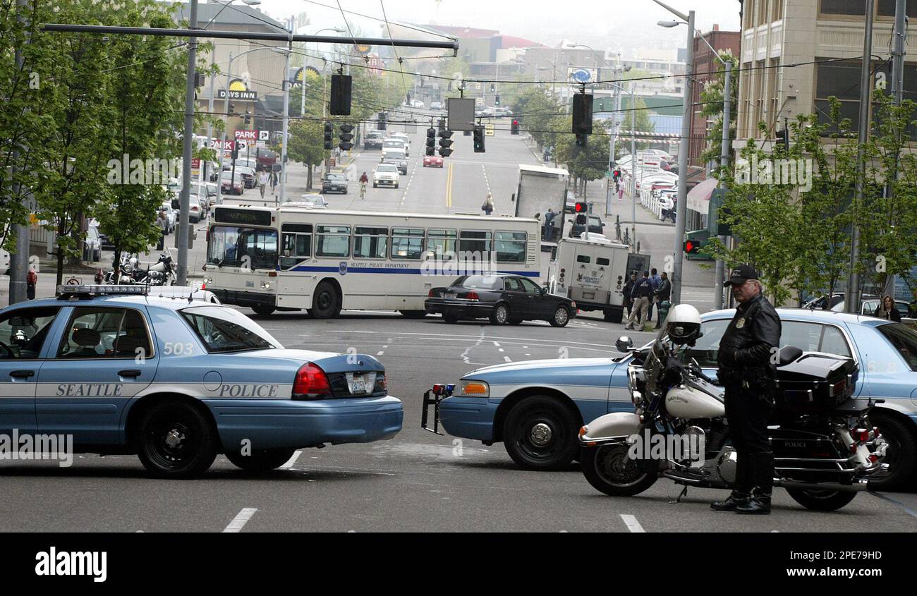 Police vehicles and a bus are used to block off a street near the ...