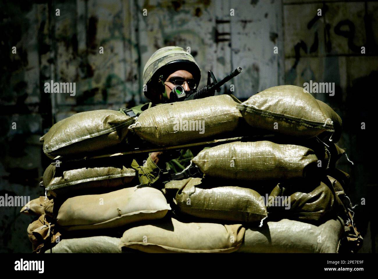 An Israeli soldier takes a position behind sandbags between the Jewish ...