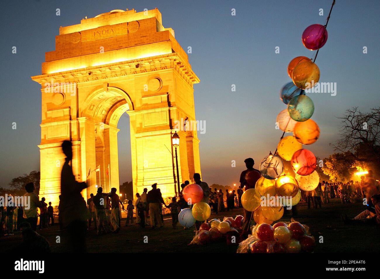 An Indian vendor sells balloons as families gather in a park ...