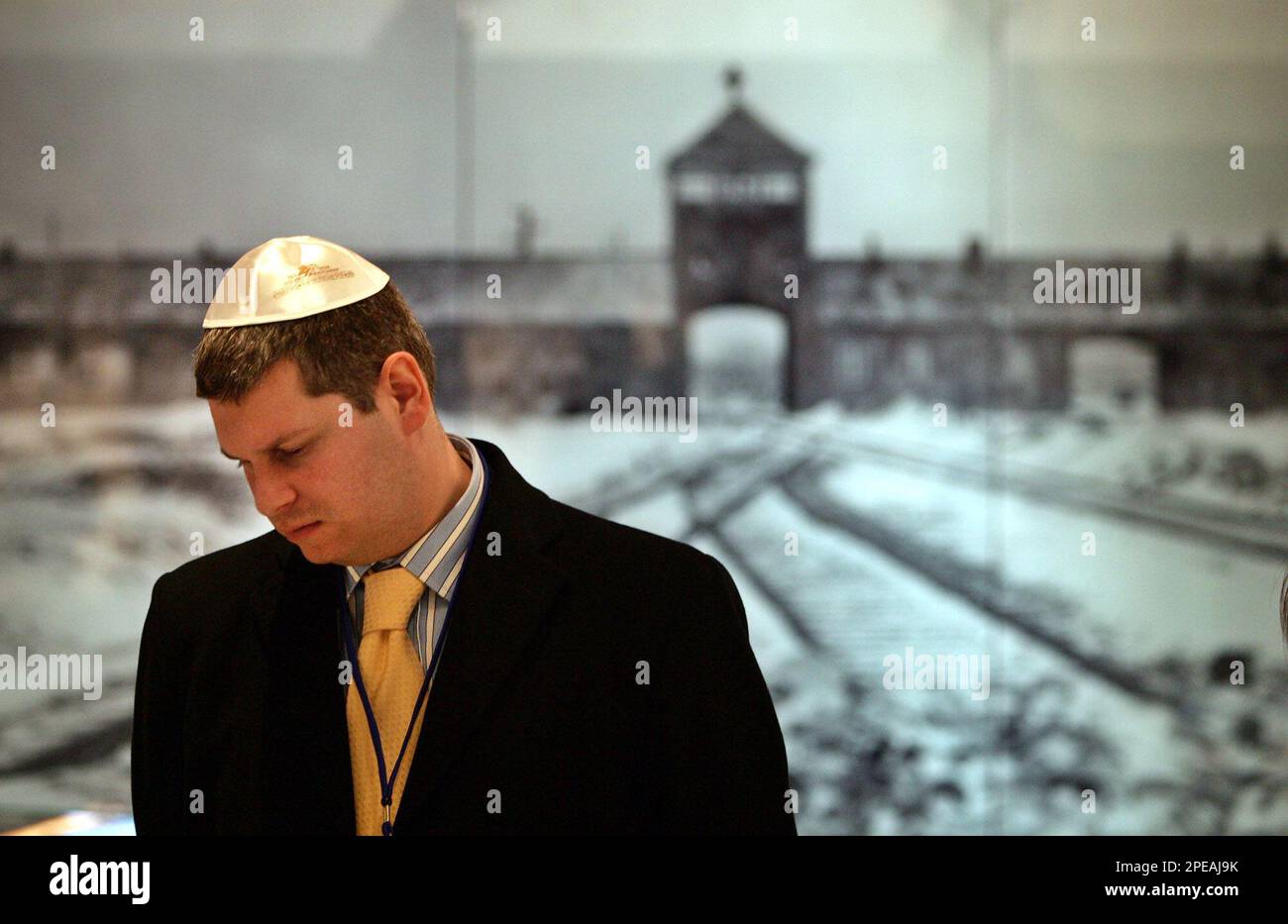 A visitor stands in front of a picture of death camp Auschwitz-Birkenau ...