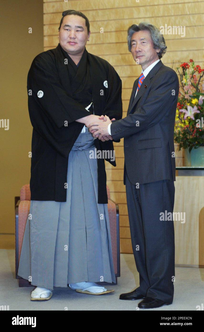 Sumo's grand champion Asashoryu, left, in formal attire, shakes hands ...