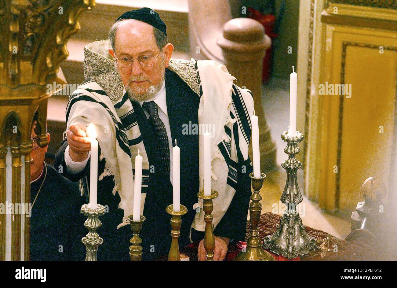 Romania's Chief Rabbi Menahem Hacohen lights the first of six candles ...