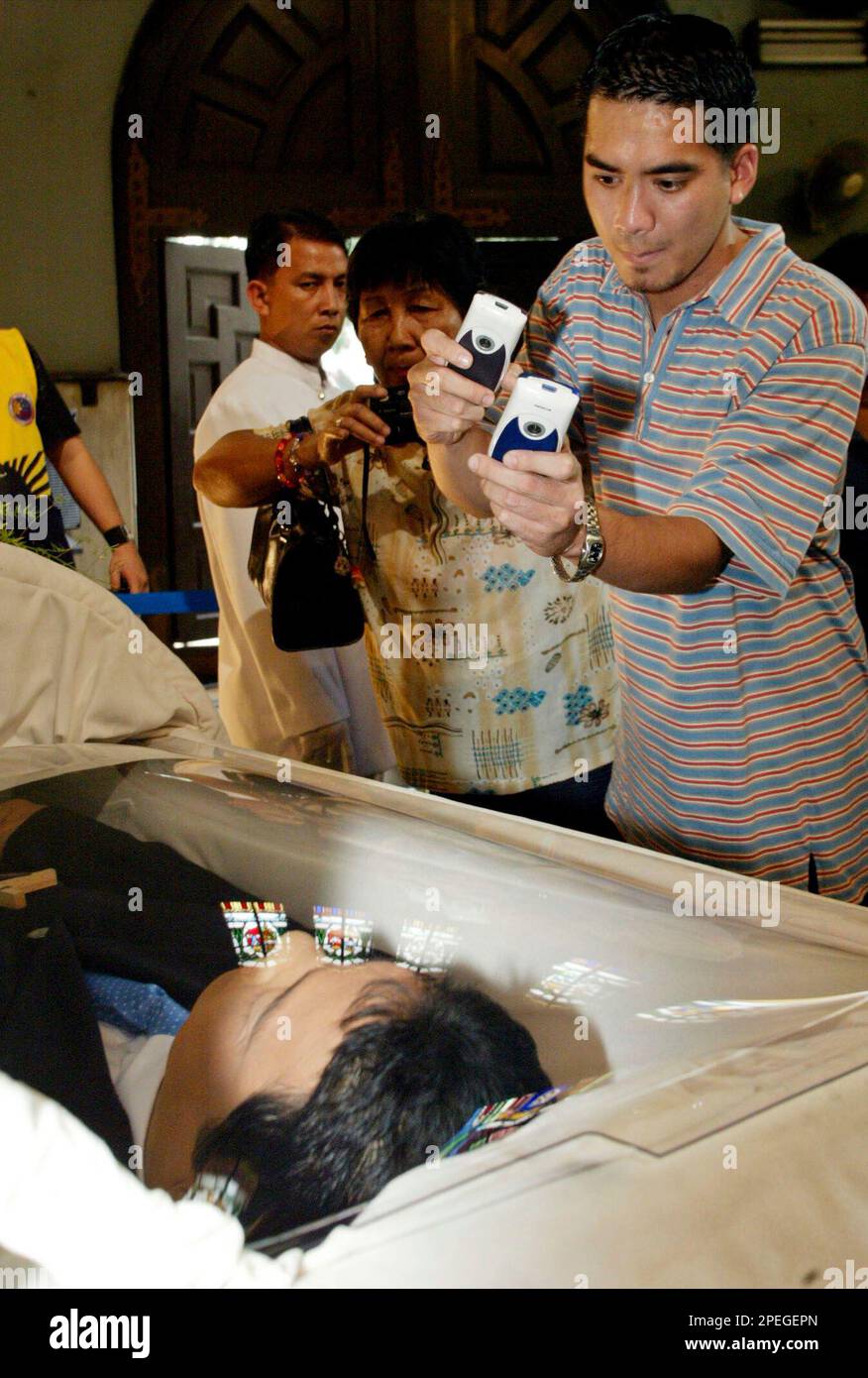 Supporters of former Presidential candidate Fernando Poe Jr. take his photo as they file past ...