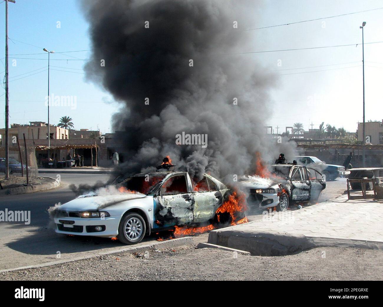 ** FILE ** Two Iraqi police patrol cars burn after they were attacked ...