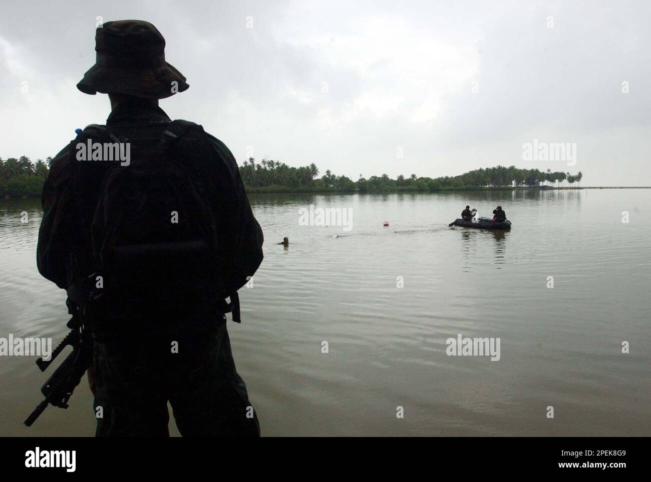 A Thai soldier looks at a group of frogmen dive in a search for weapons ...