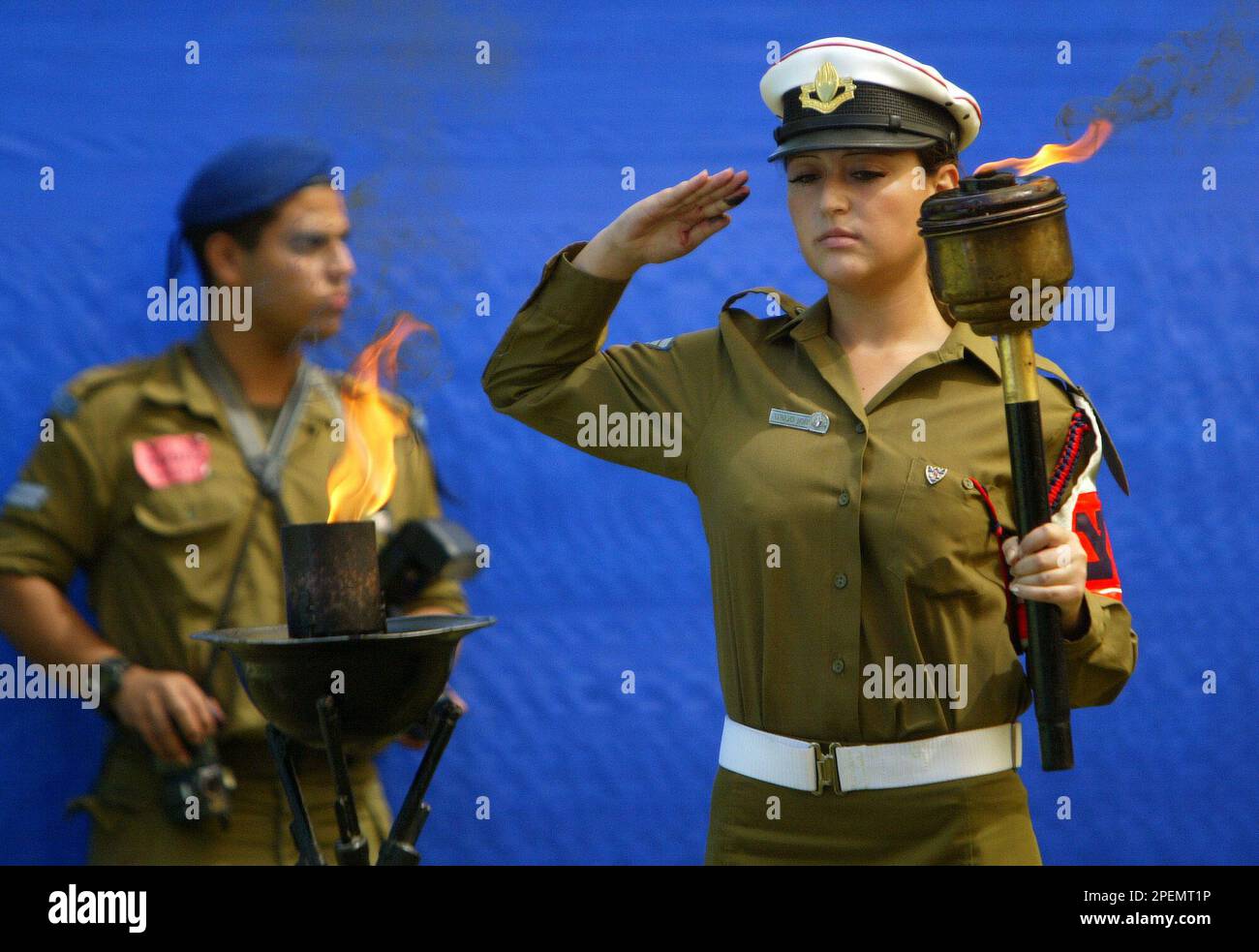 An Israeli soldier from an honor guard carries a torch and salutes a ...