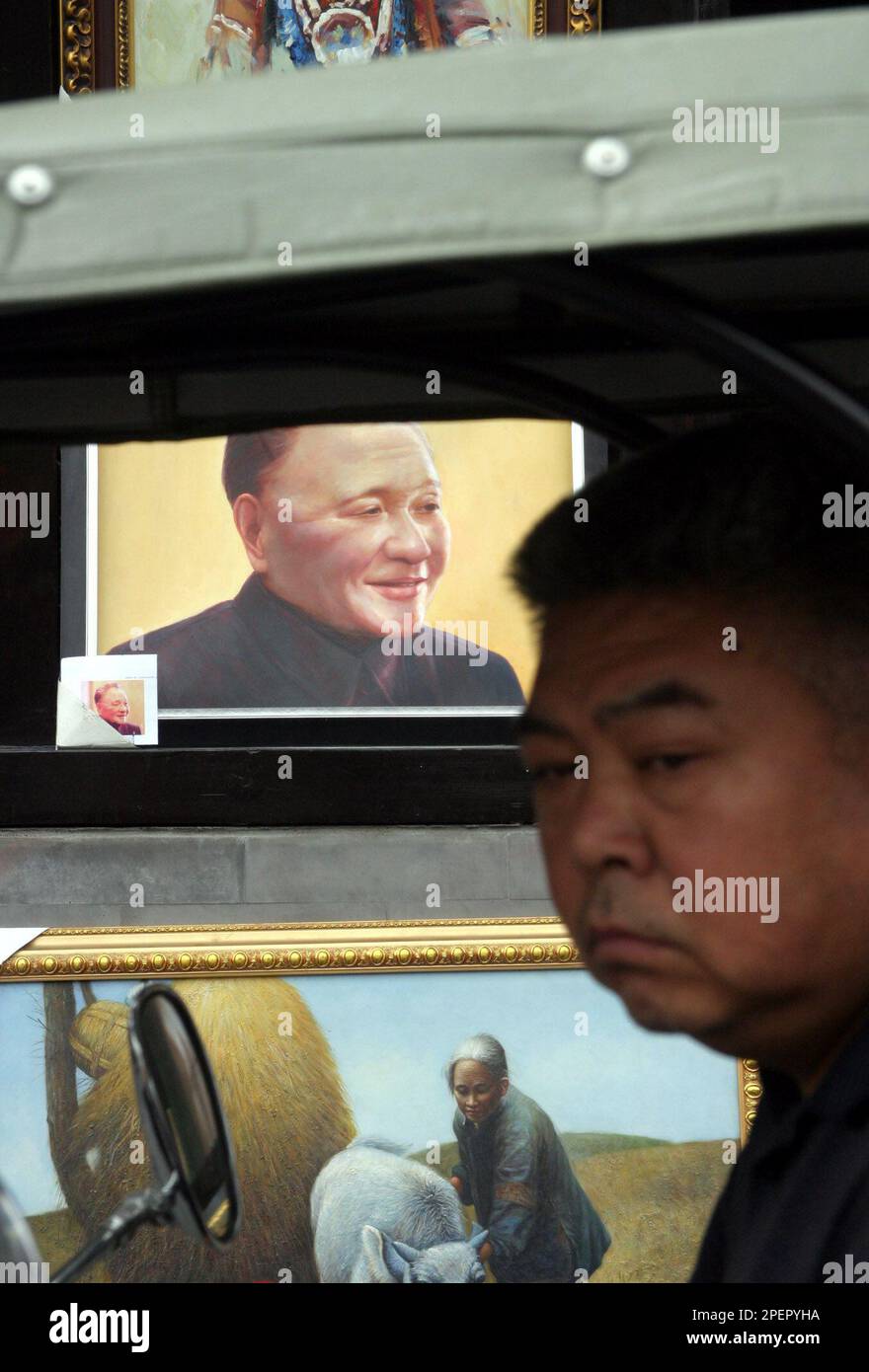 A Chinese man looks out from his tricycle near a portrait of former ...
