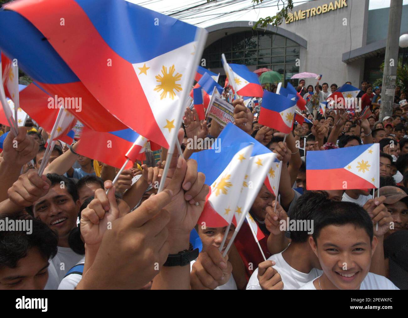 A crowd of supporters wave Philippine flags as they cheer the inauguration of Philippine ...