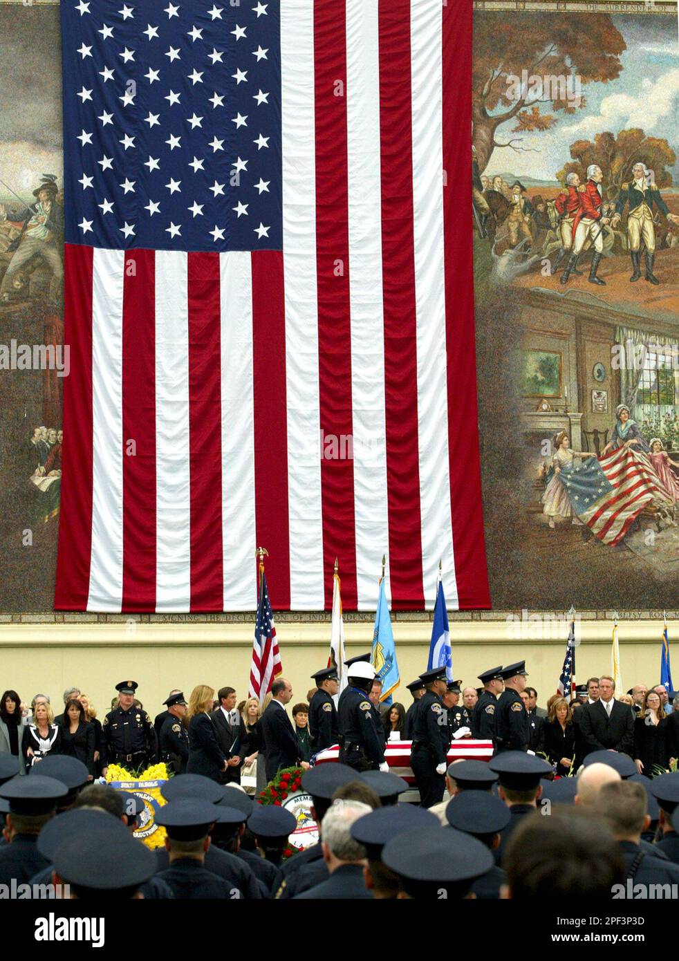 Family members, friends, and police officers rise as the casket of ...