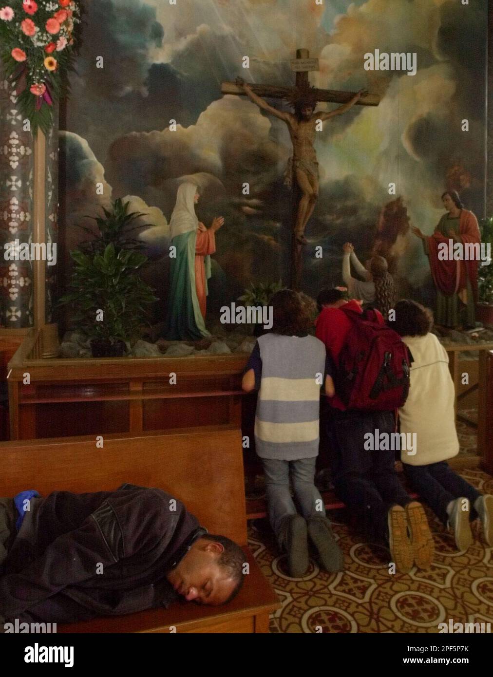 A Costa Rican man sleeps on a church pew as other Catholic faithful ...