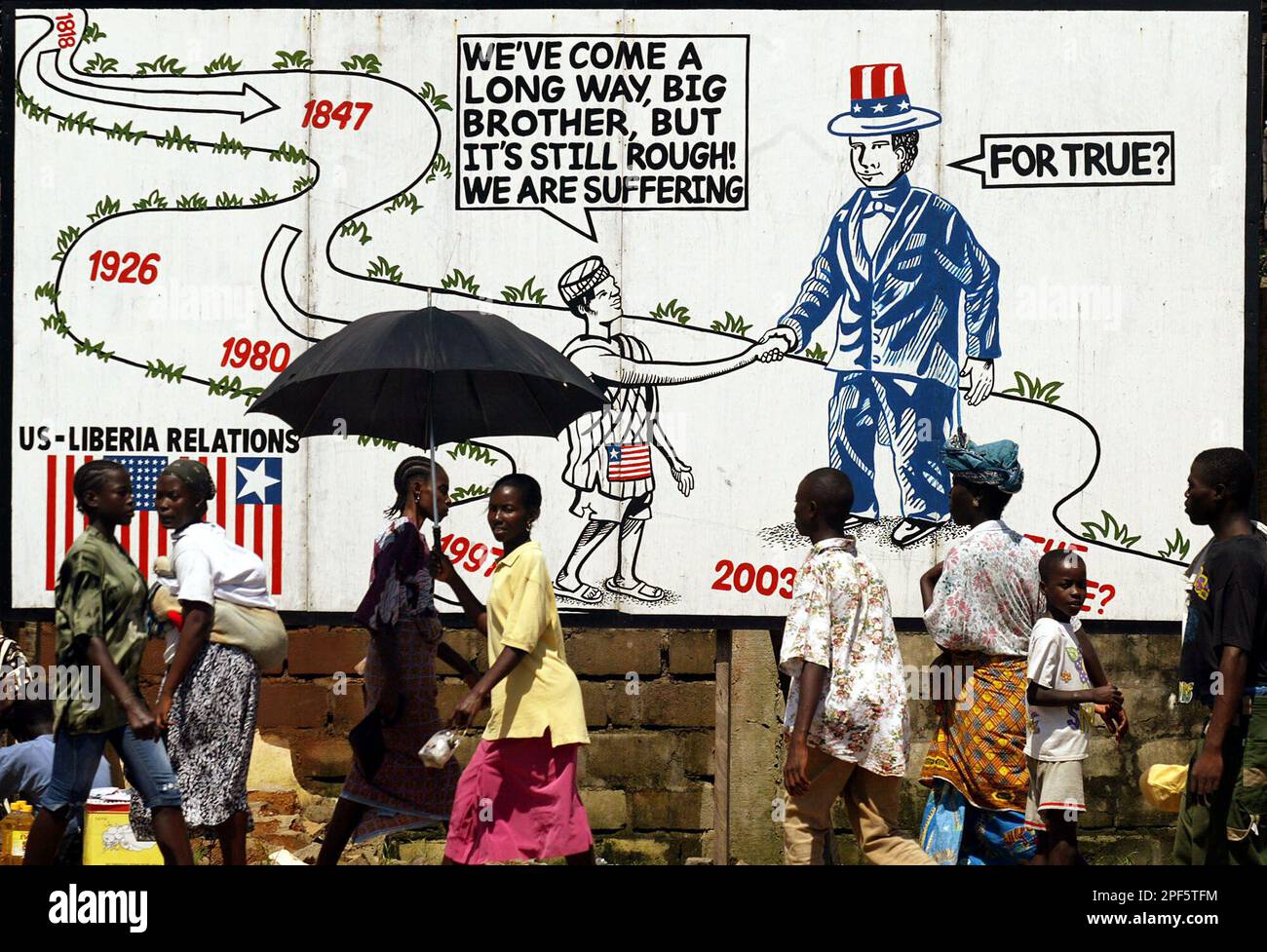 Liberians walk past a sign dedicated to US-Liberia relations near the ...