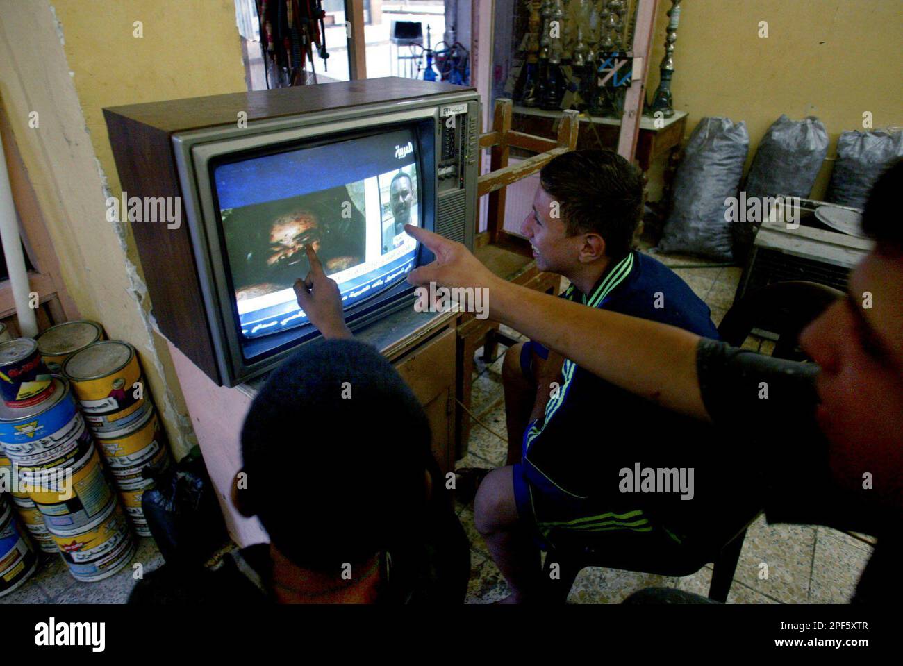 Iraqi people watch television in Baghdad, Iraq, Thursday July 24, 2003 ...