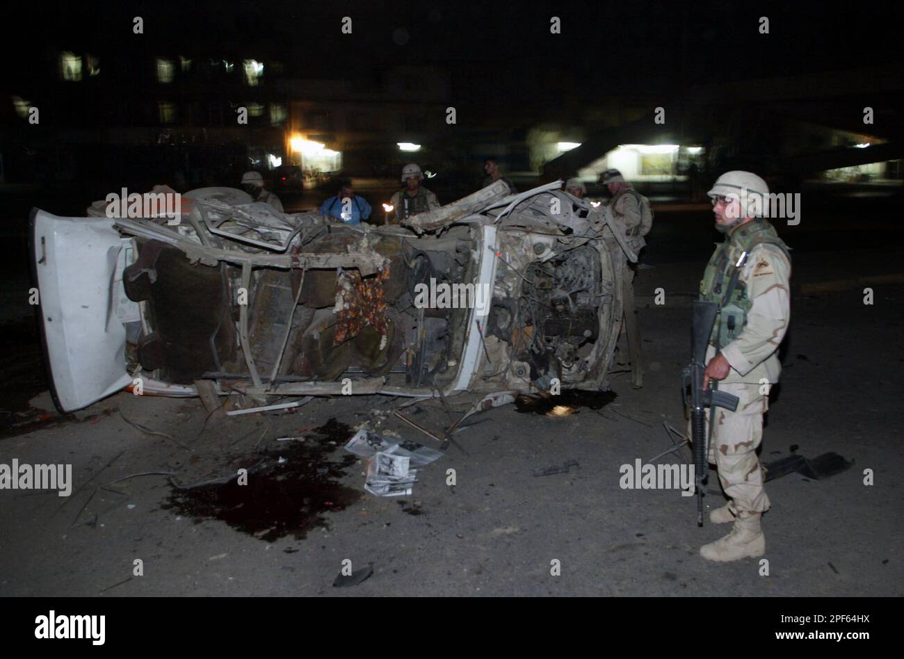 U.S. Army soldiers stand near a car that exploded in Baghdad Sunday ...