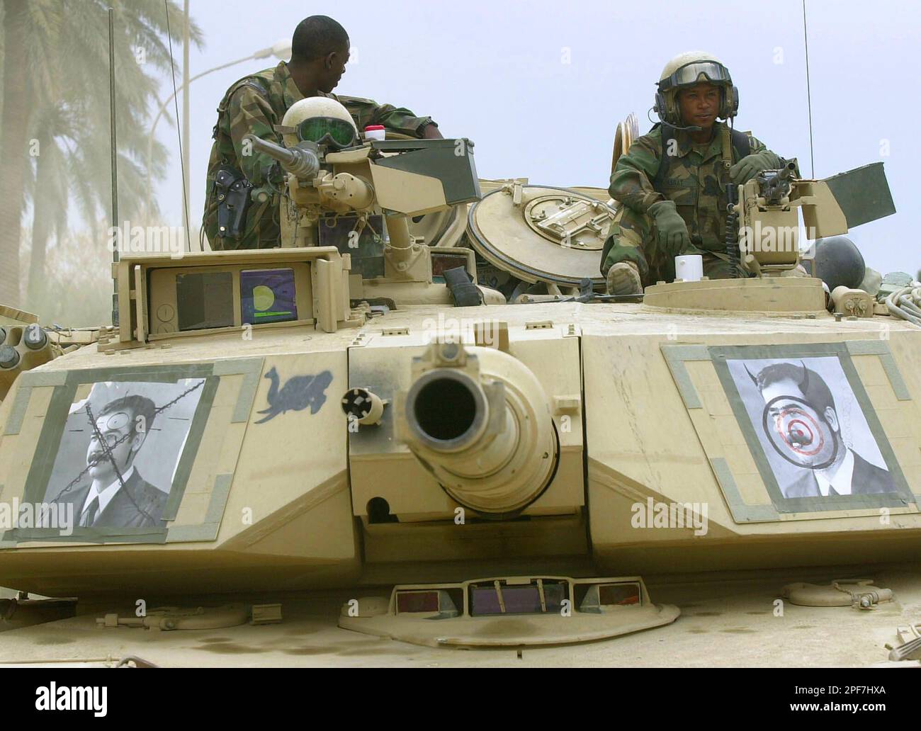 U.S. soldiers sit on top of a tank decorated with portraits of Saddam ...